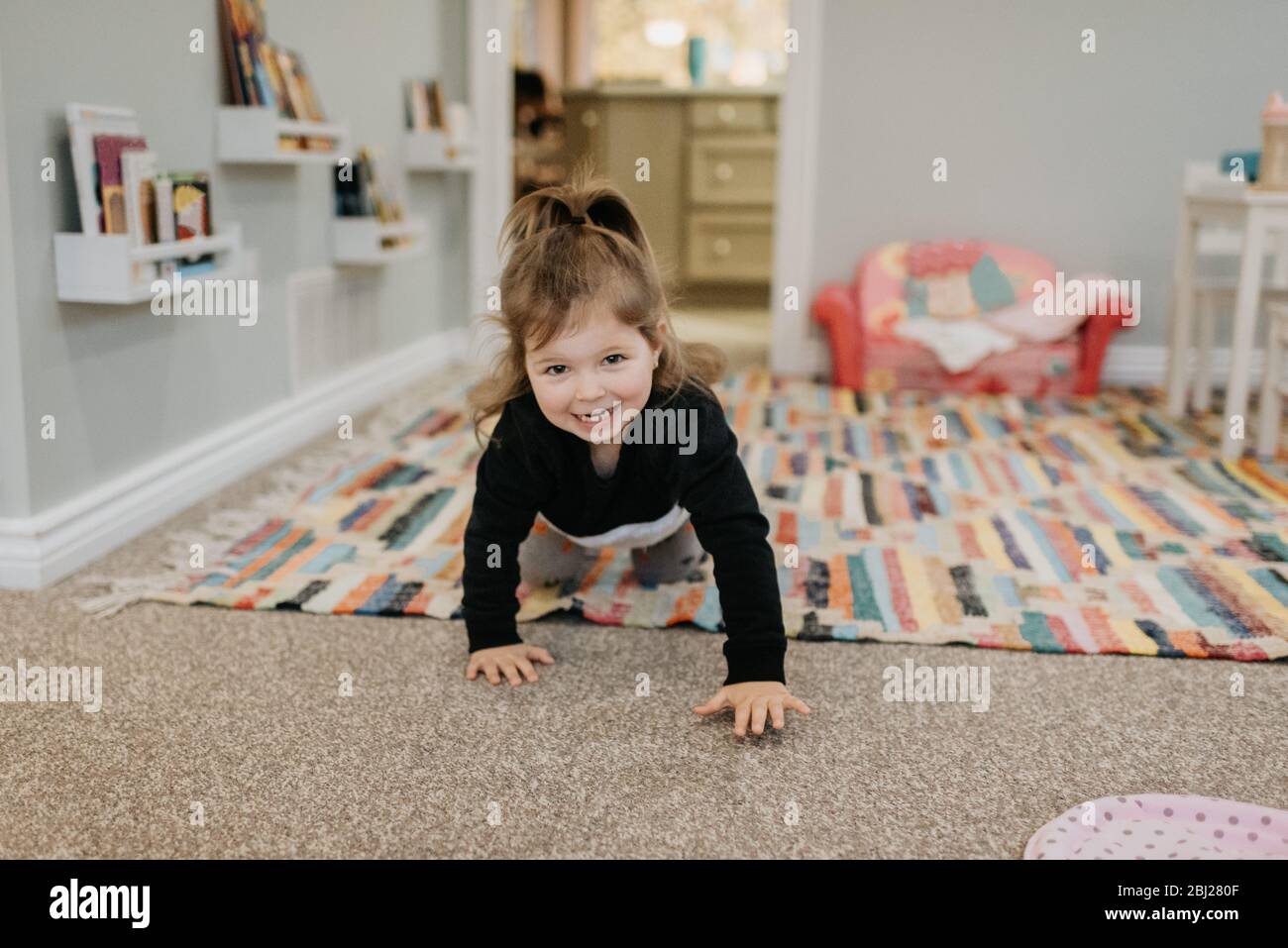 A young girl crawling towards the camera and smiling Stock Photo - Alamy