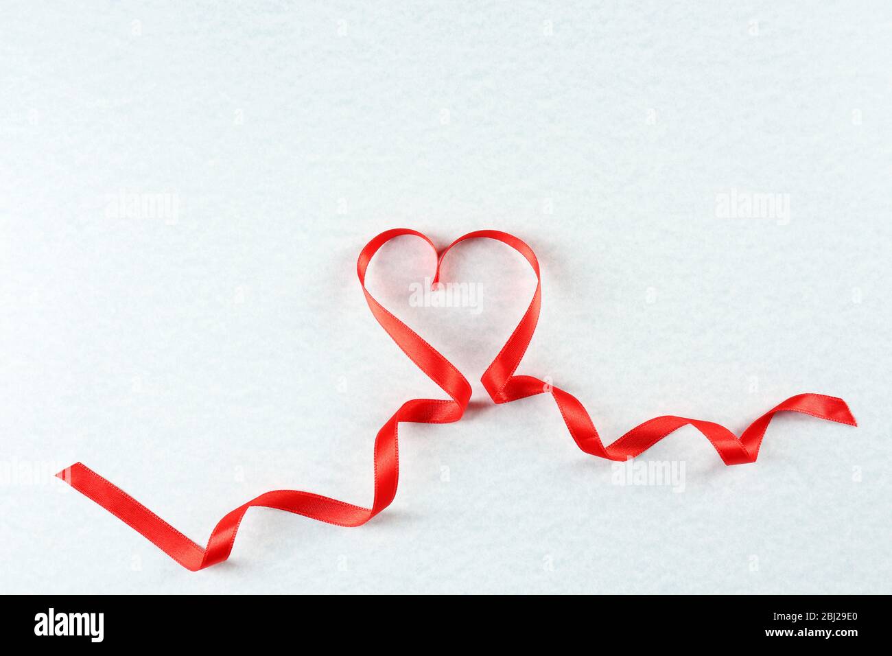 Red heart ribbon on light grey textured background Stock Photo - Alamy