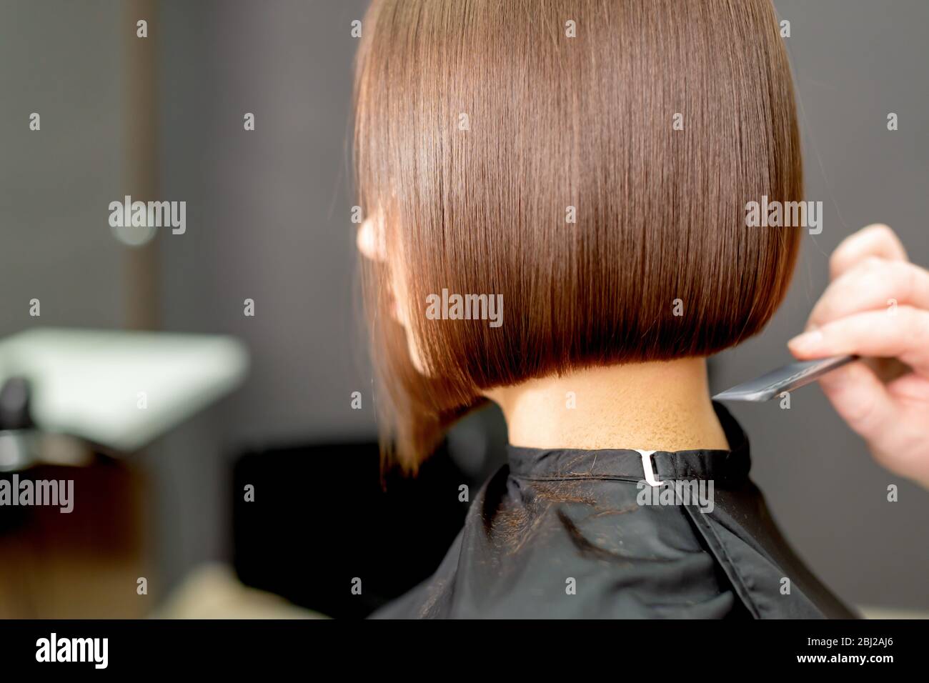 Close-up of hairdresser hand is combing short hair of woman in hair ...