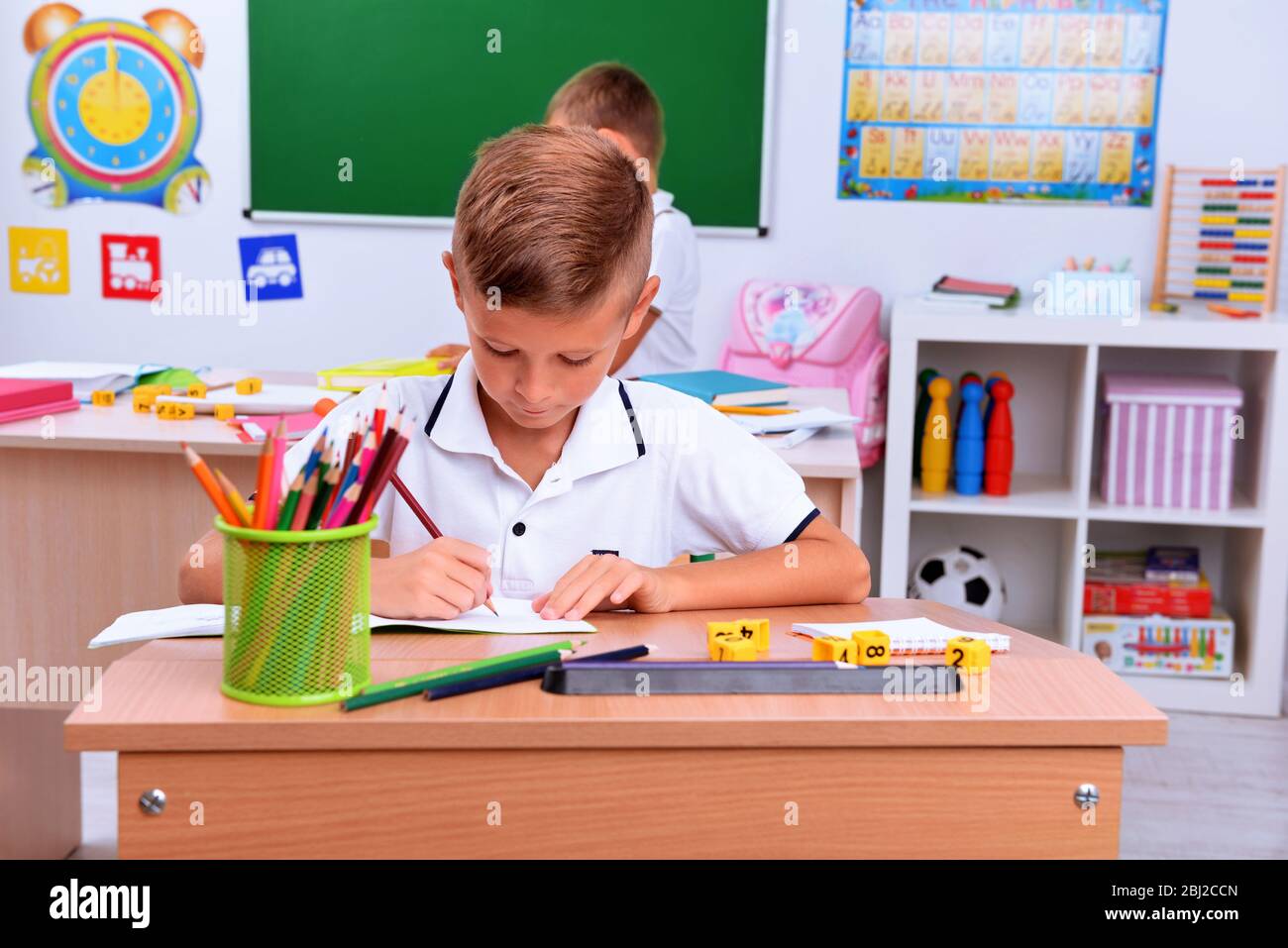 Little boy drawing at the desk in classroom Stock Photo - Alamy