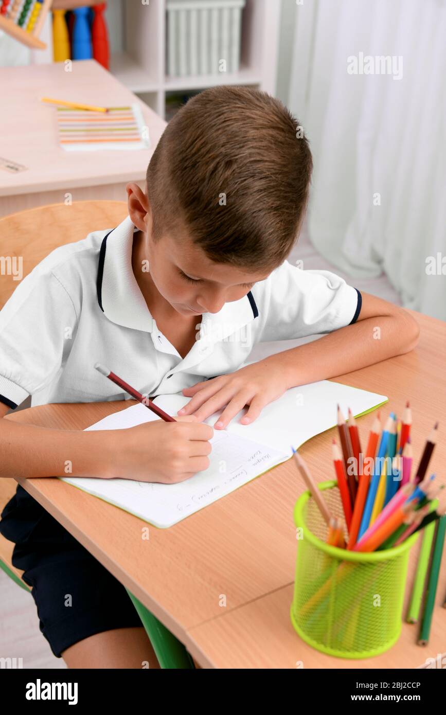 Little boy drawing at the desk in classroom Stock Photo - Alamy