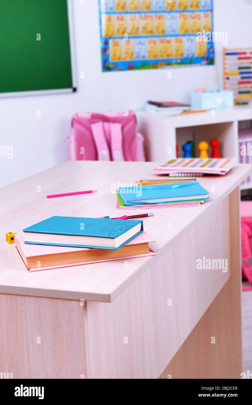 Desktop with books in classroom Stock Photo - Alamy