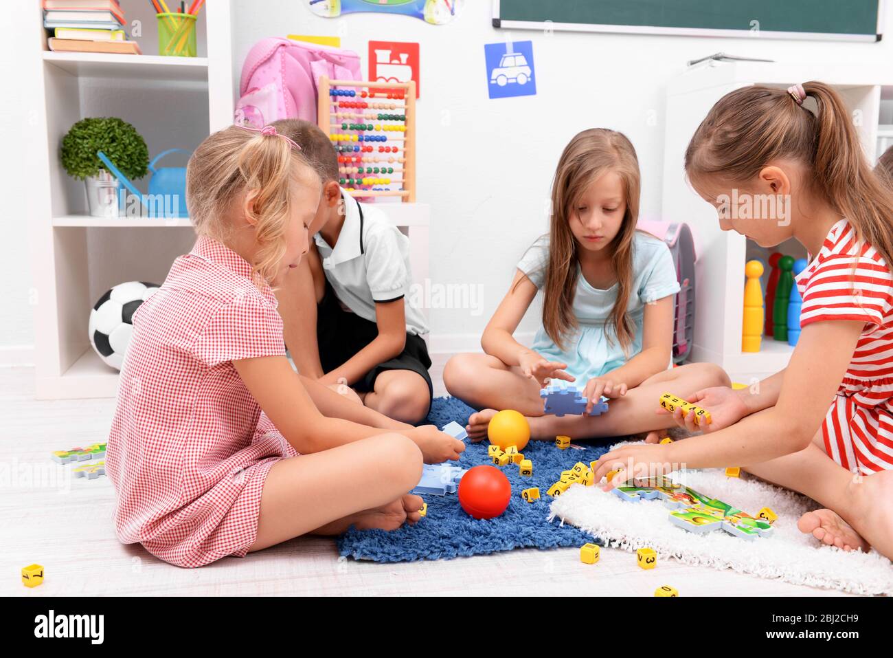 Group of children playing on floor in classroom Stock Photo - Alamy