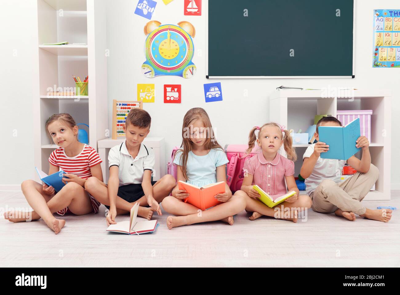 Row of children reading on floor in classroom Stock Photo - Alamy