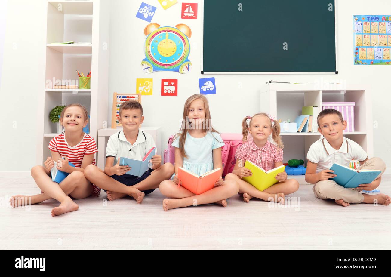 Row of children reading on floor in classroom Stock Photo - Alamy