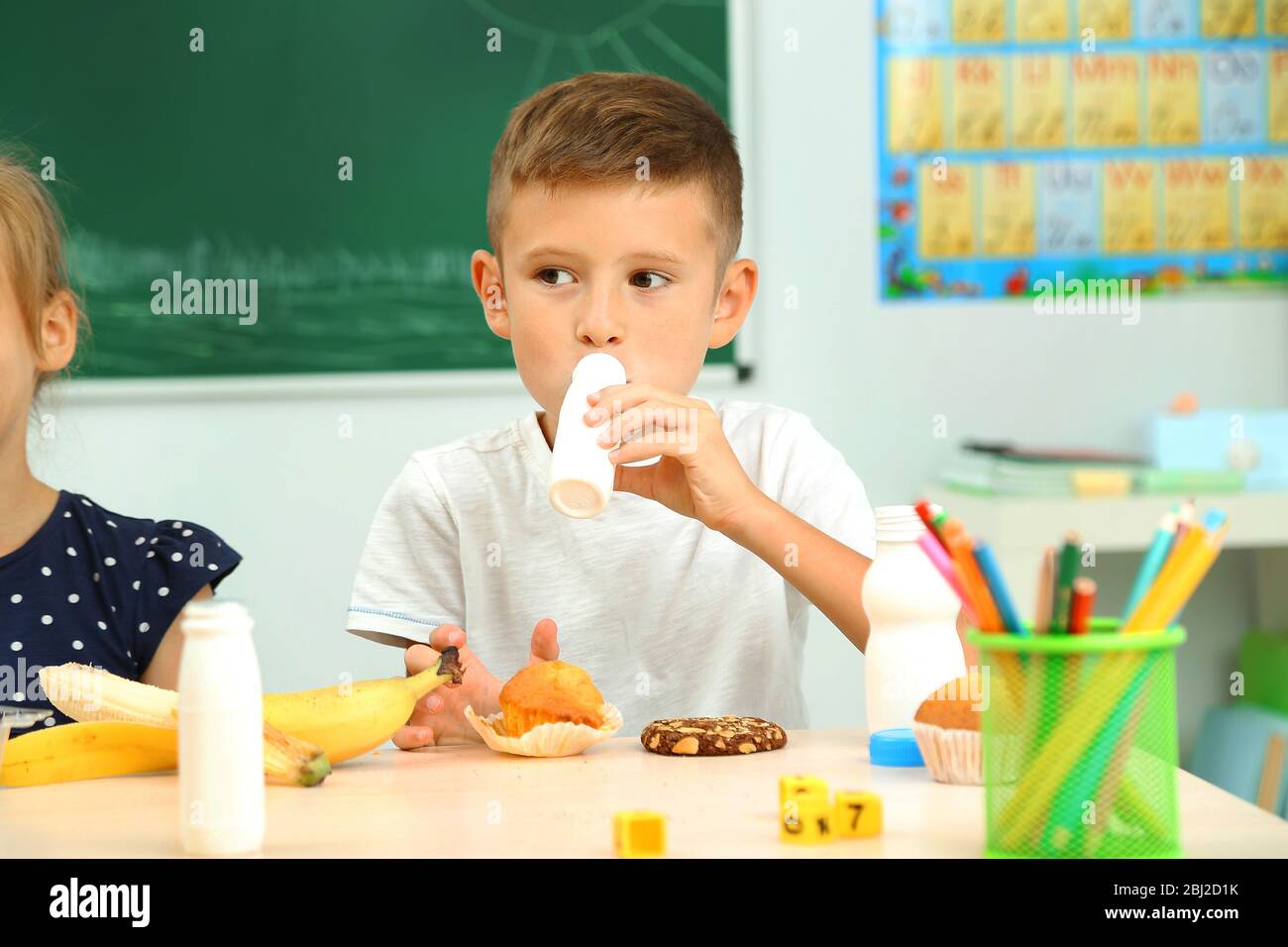 Cute boy at lunch time in classroom Stock Photo - Alamy