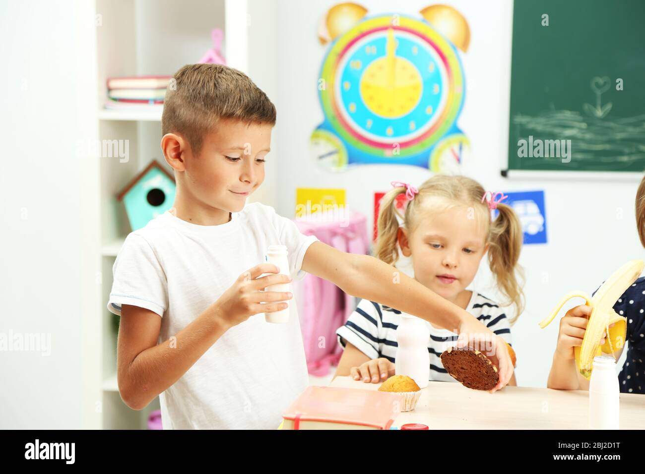 Cute children at lunch time in classroom Stock Photo - Alamy