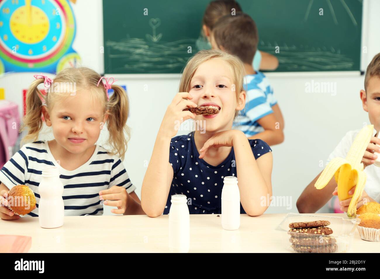 Cute children at lunch time in classroom Stock Photo - Alamy