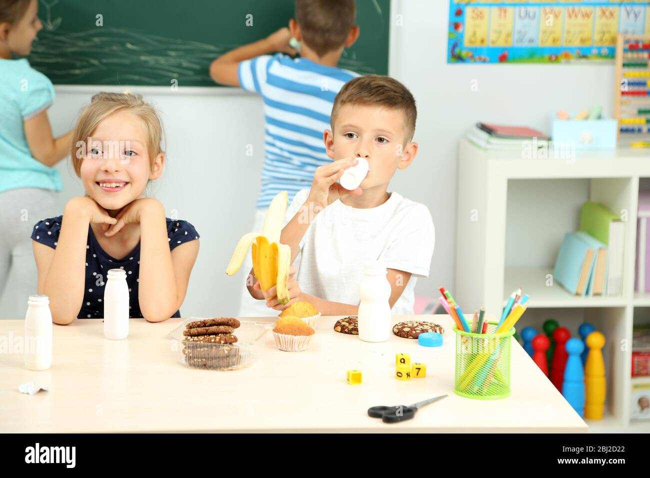 Cute children at lunch time in classroom Stock Photo - Alamy