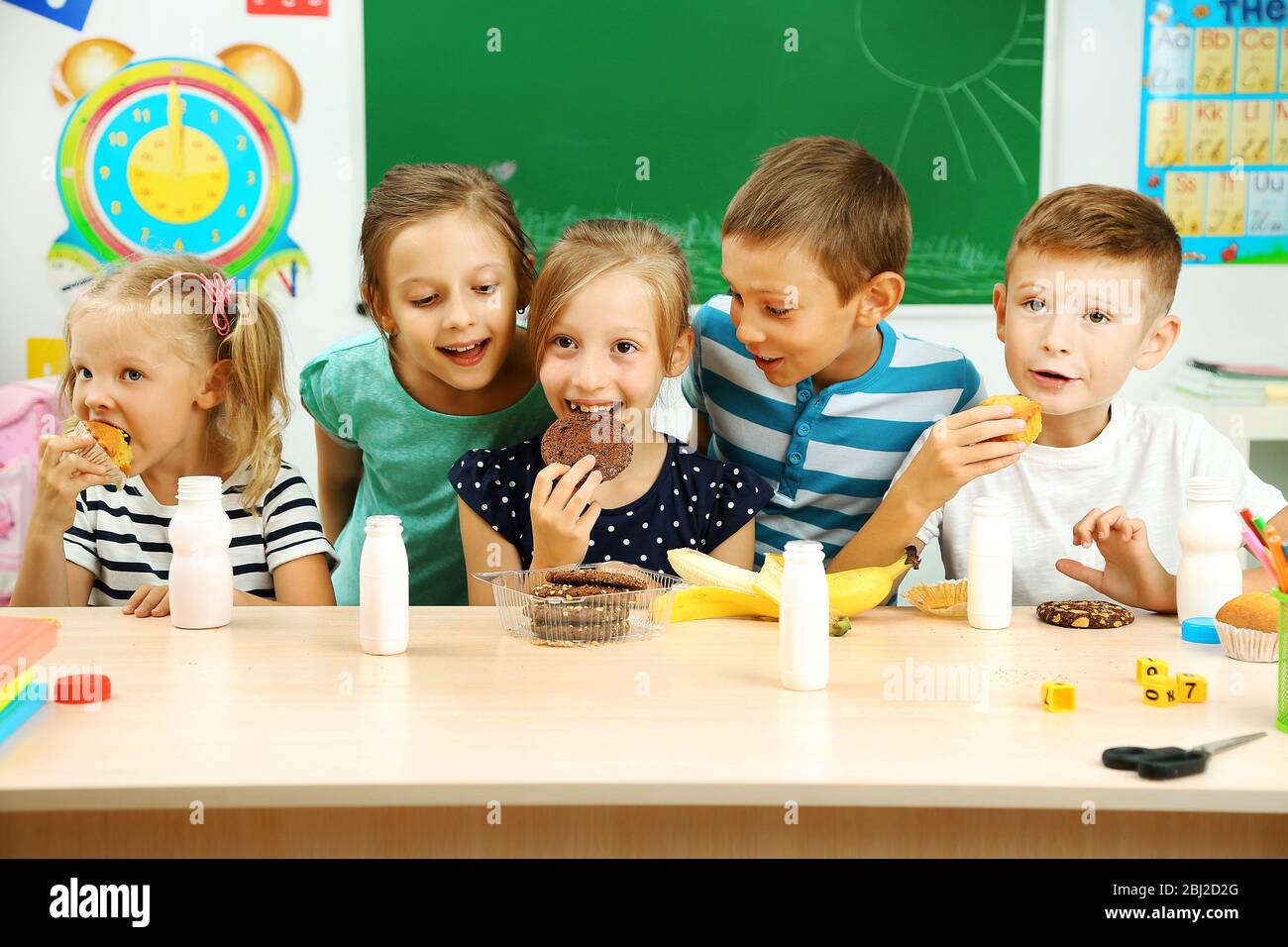 Cute children at lunch time in classroom Stock Photo - Alamy