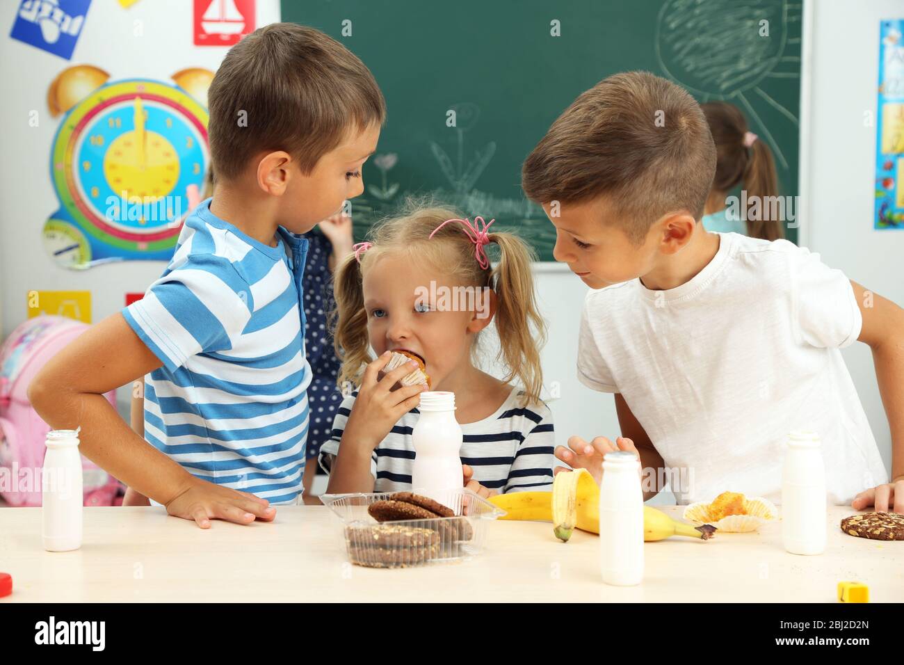 Cute children at lunch time in classroom Stock Photo - Alamy