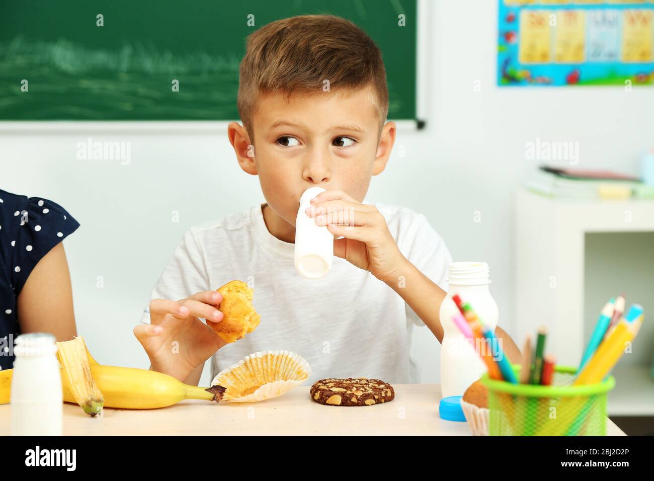 Cute boy at lunch time in classroom Stock Photo - Alamy