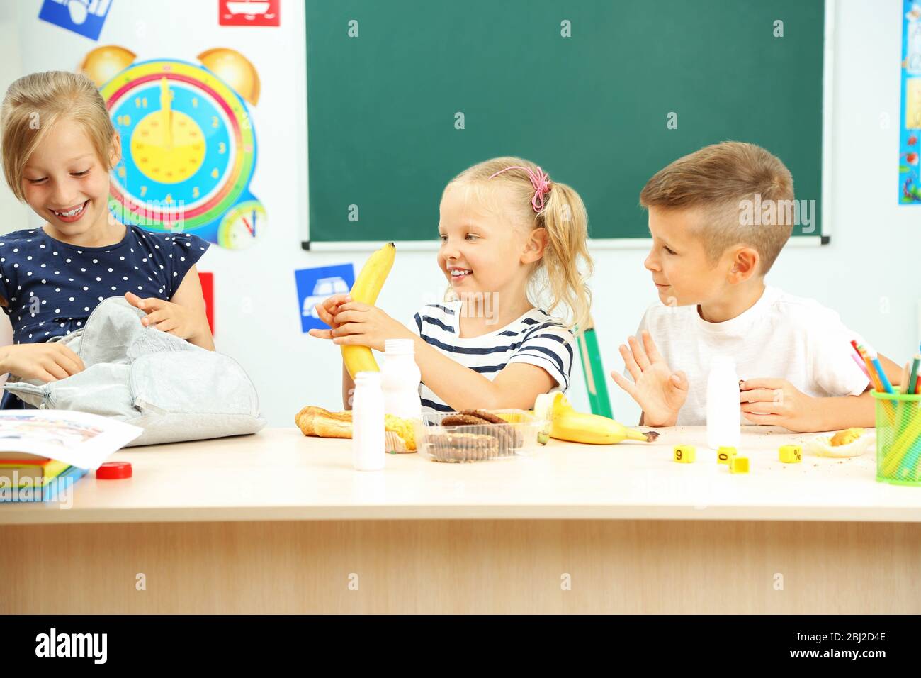 Cute children at lunch time in classroom Stock Photo - Alamy