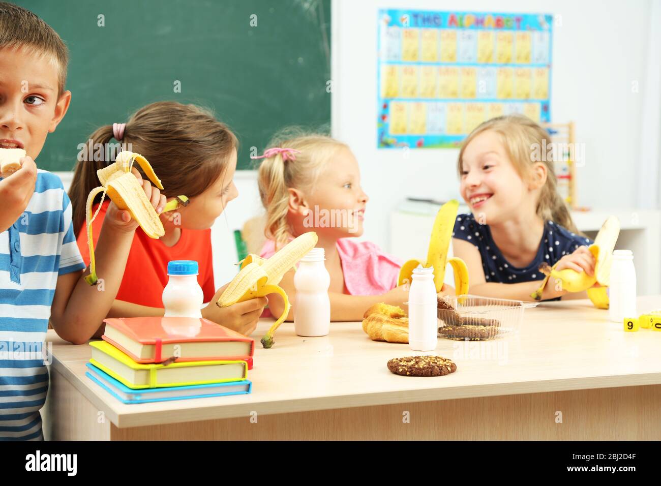 Cute children at lunch time in classroom Stock Photo - Alamy