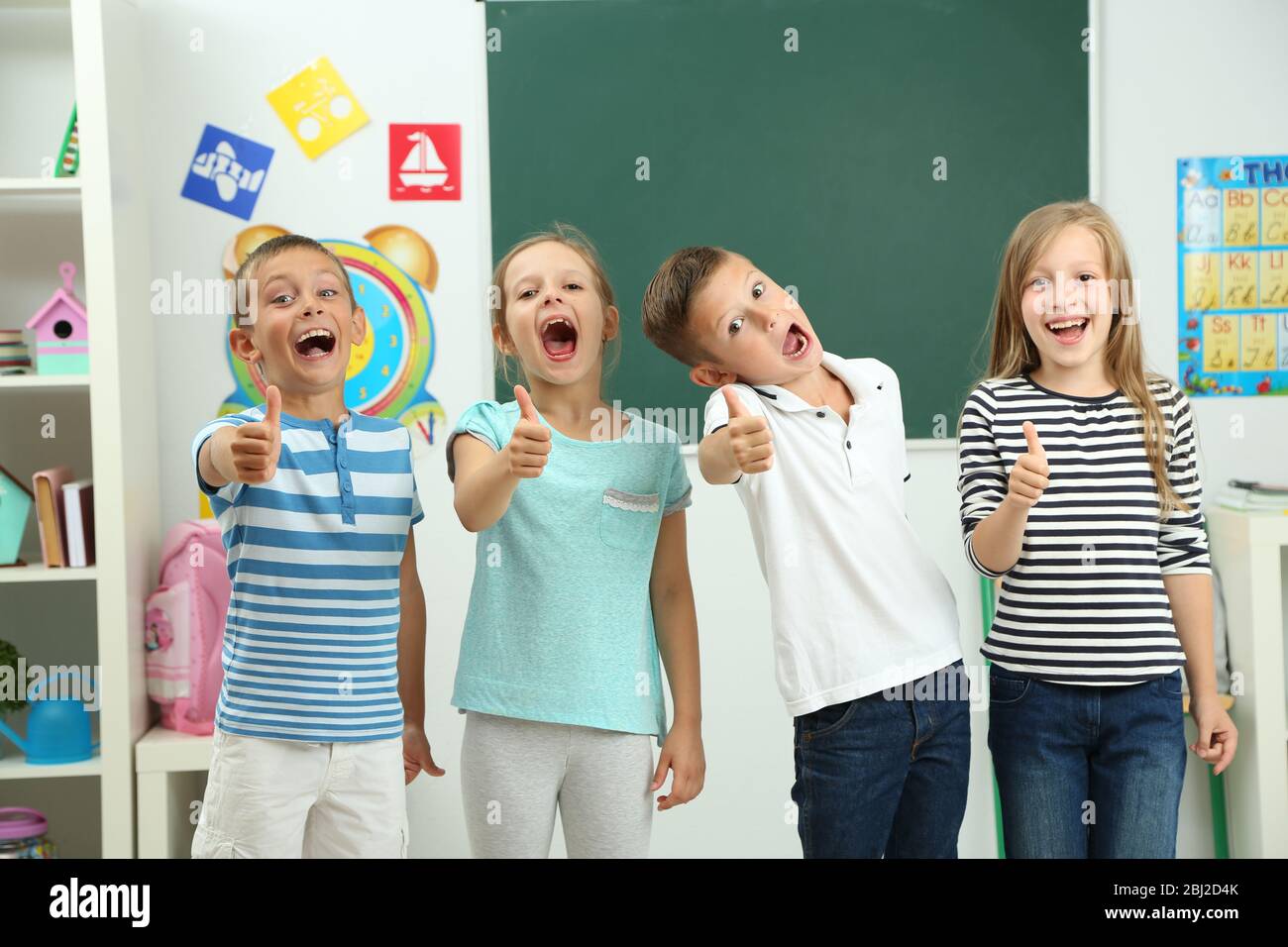 Portrait of happy classmates looking at camera in classroom Stock Photo ...
