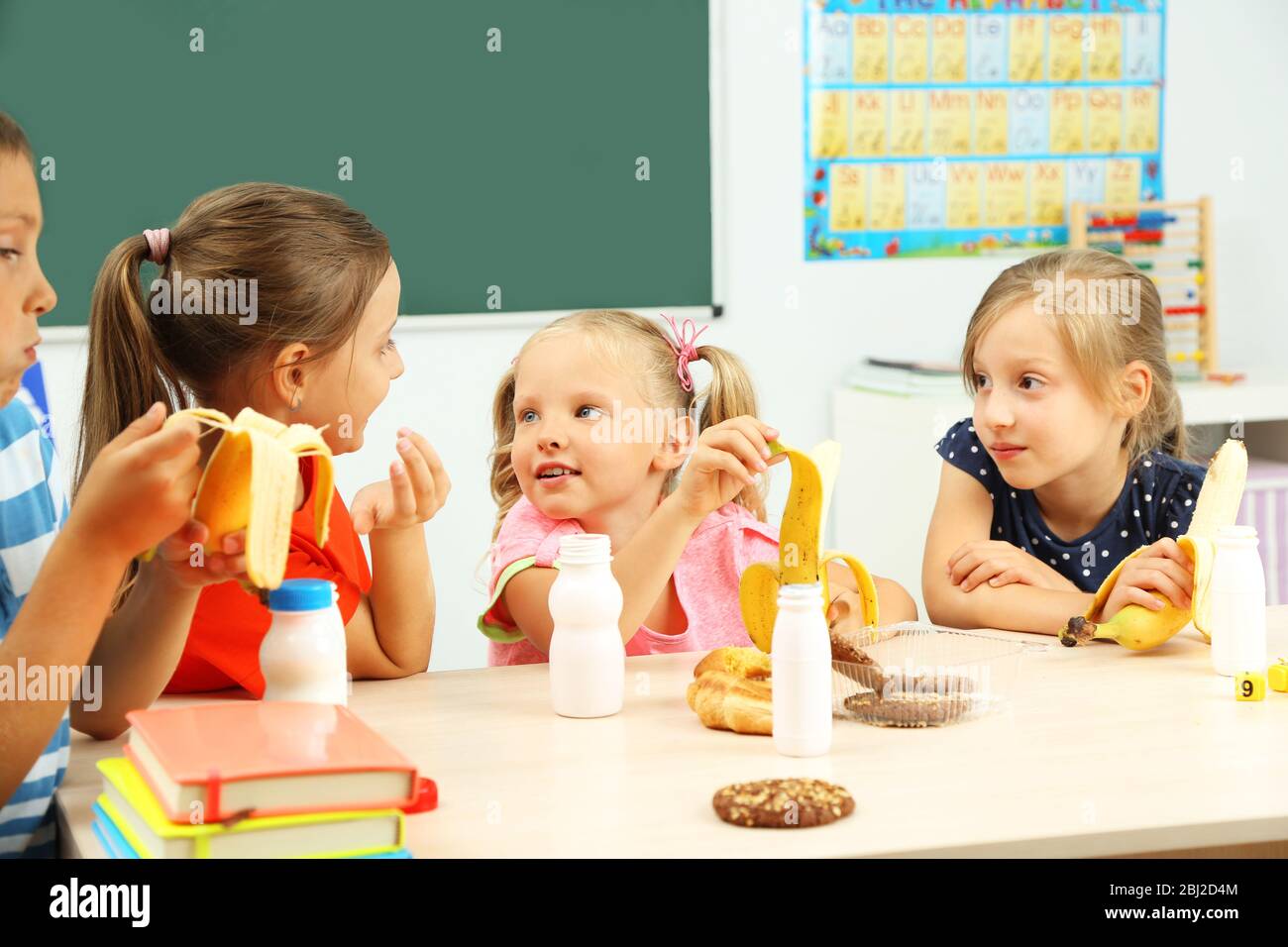 Cute children at lunch time in classroom Stock Photo - Alamy