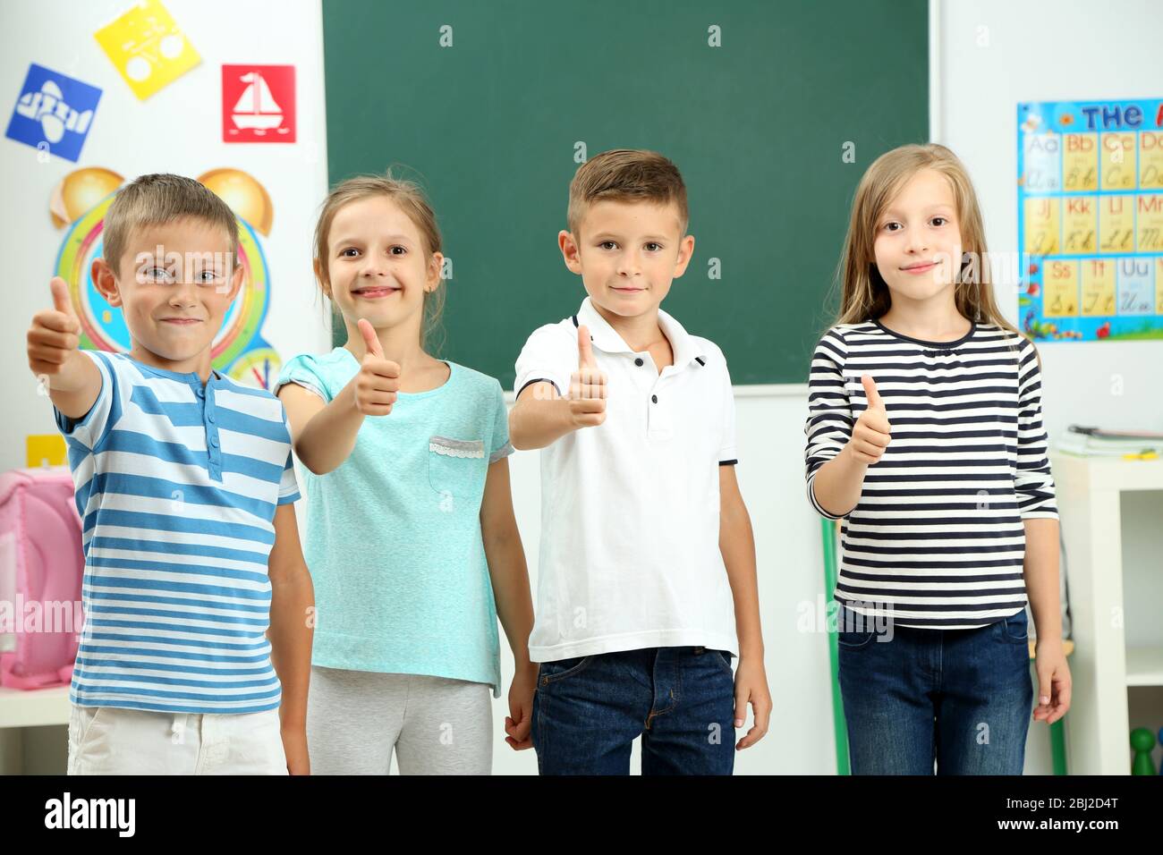 Portrait of happy classmates looking at camera in classroom Stock Photo ...