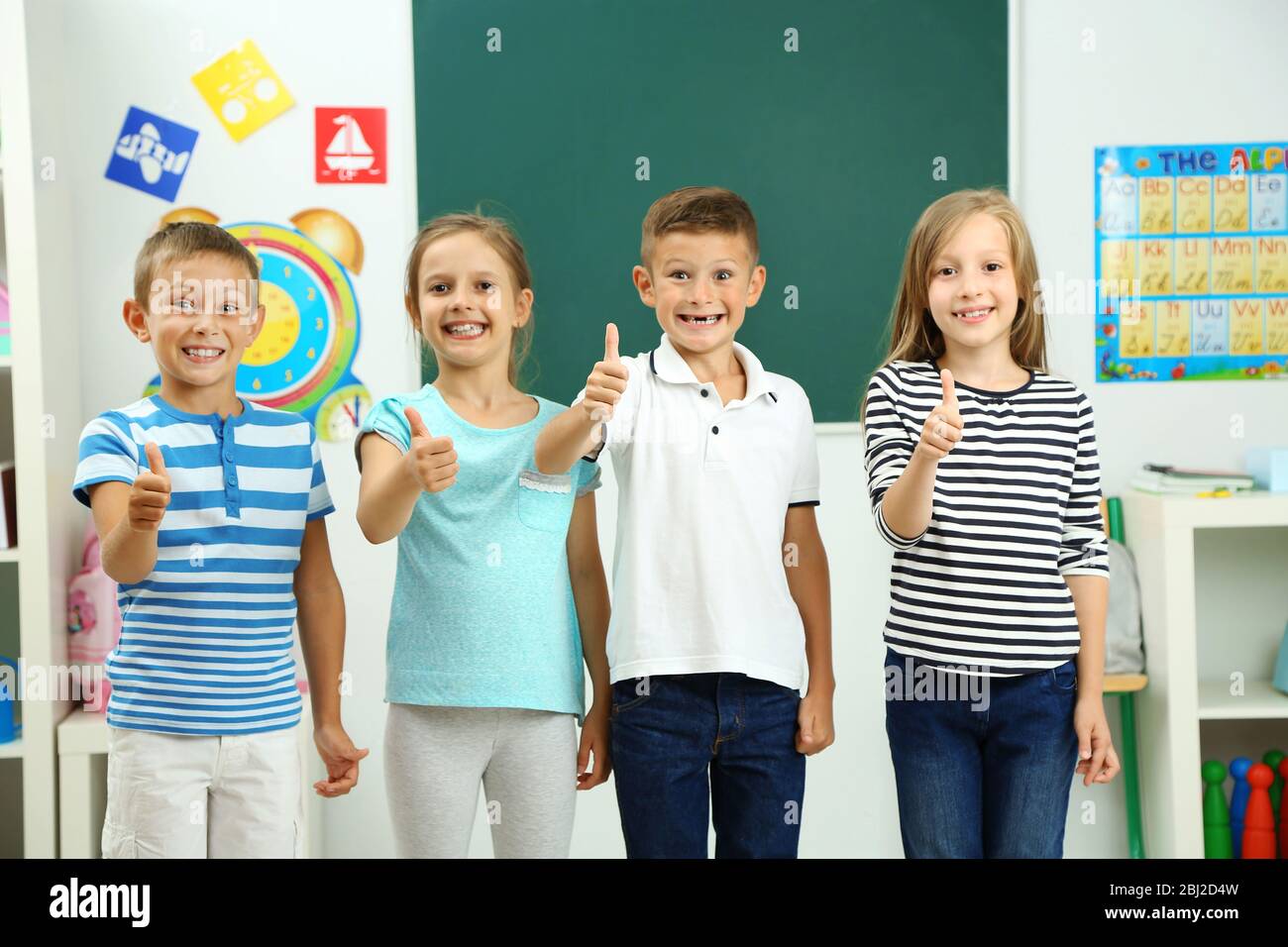Portrait of happy classmates looking at camera in classroom Stock Photo ...
