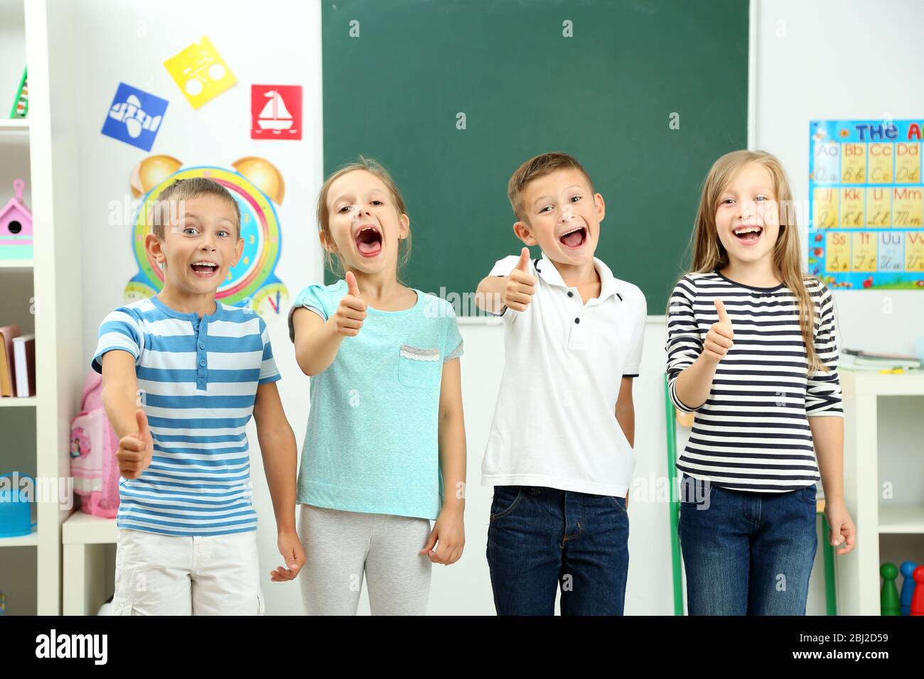 Portrait of happy classmates looking at camera in classroom Stock Photo ...