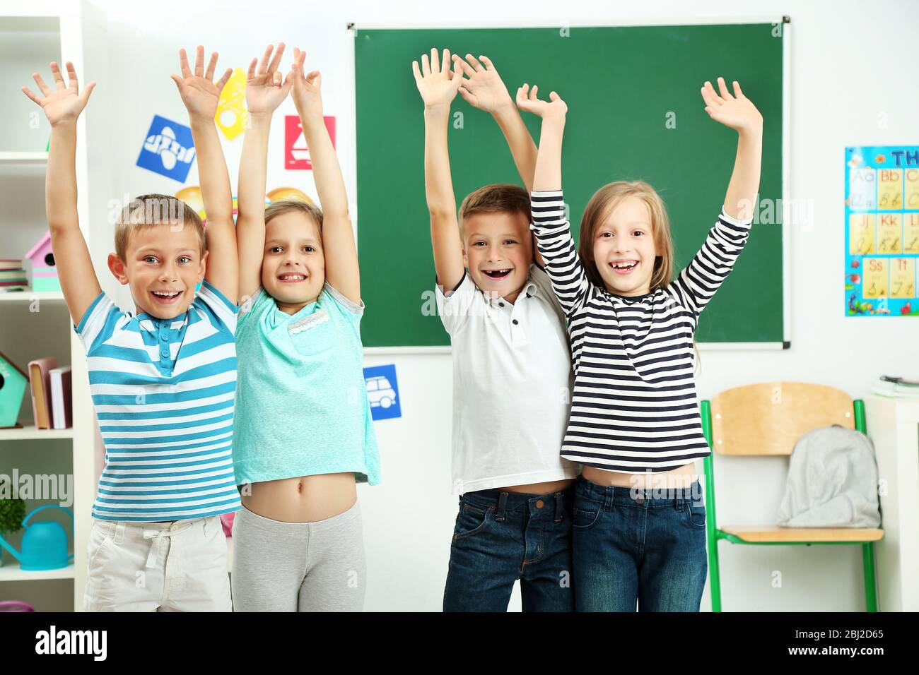 Portrait of happy classmates looking at camera in classroom Stock Photo ...