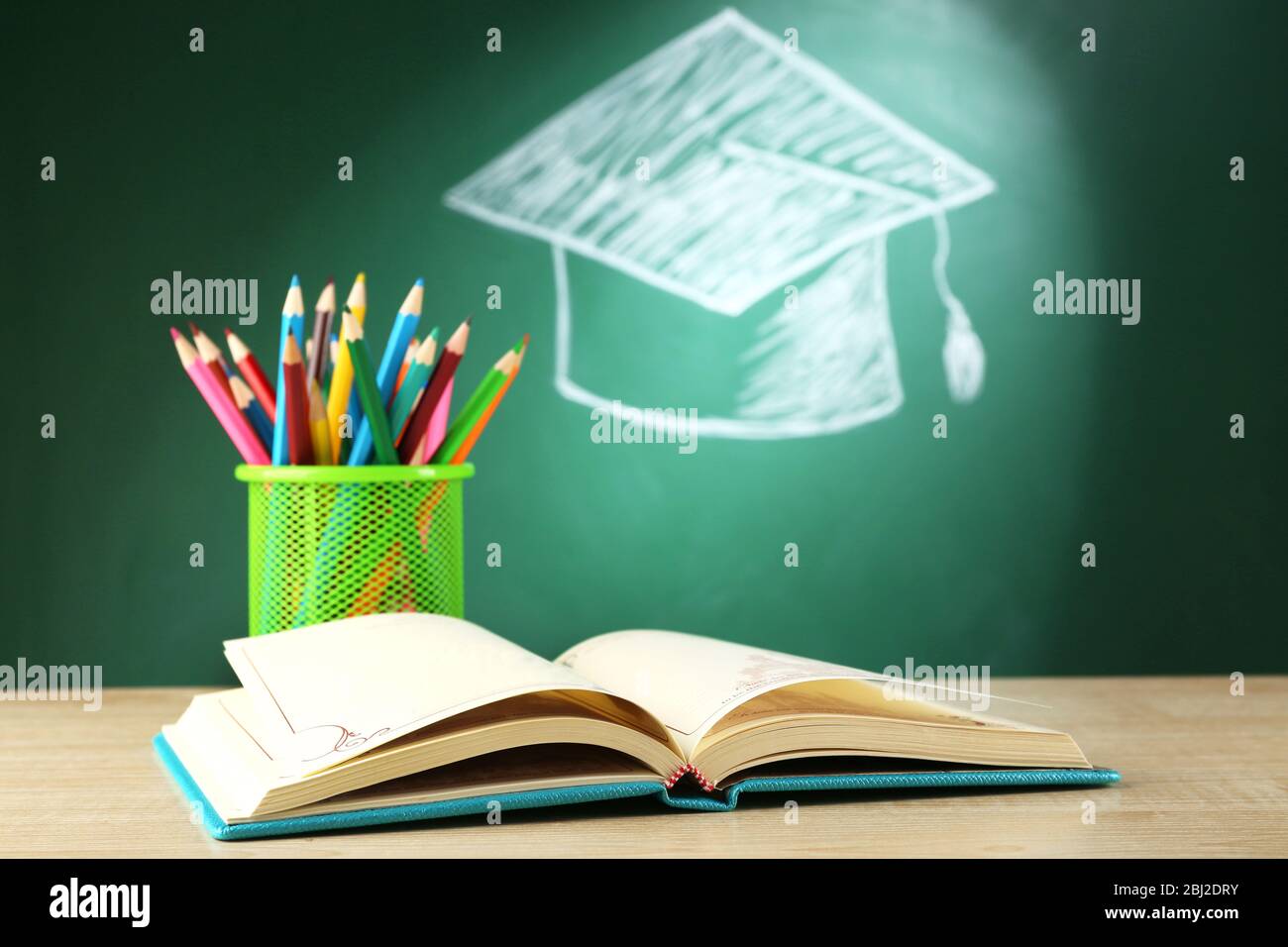 Metal cap of crayons with open book and bachelor hat drawing on ...