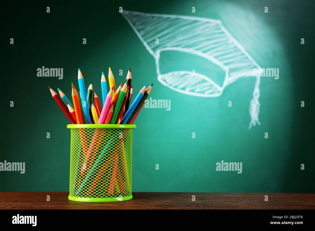 Metal cap of crayons and bachelor hat drawing on blackboard background ...