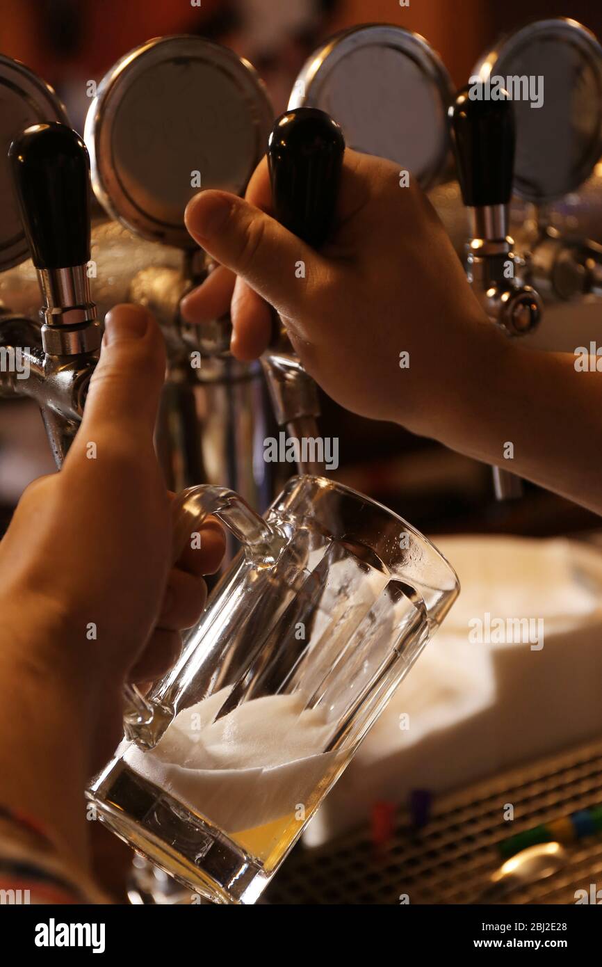 Bartender is pouring beer into glass Stock Photo - Alamy
