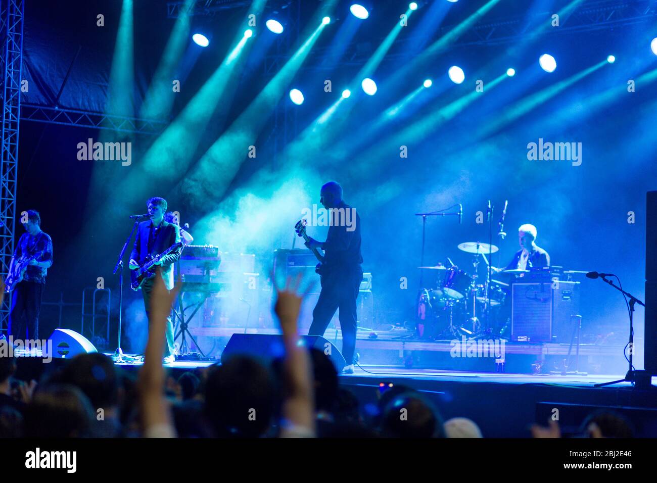 Audience with hands raised at a music festival and lights streaming ...