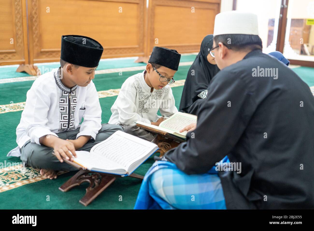 kid learning to read quran with muslim teacher or ustad Stock Photo - Alamy
