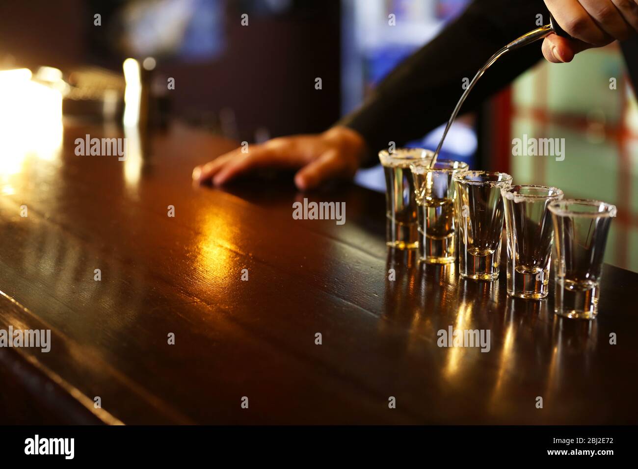 Bartender is pouring tequila into glass Stock Photo - Alamy