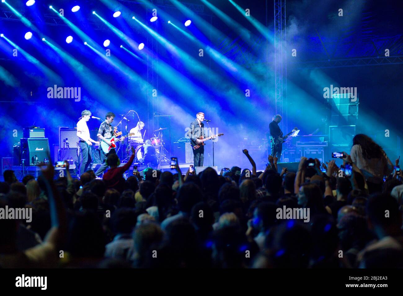 Audience with hands raised at a music festival and lights streaming ...