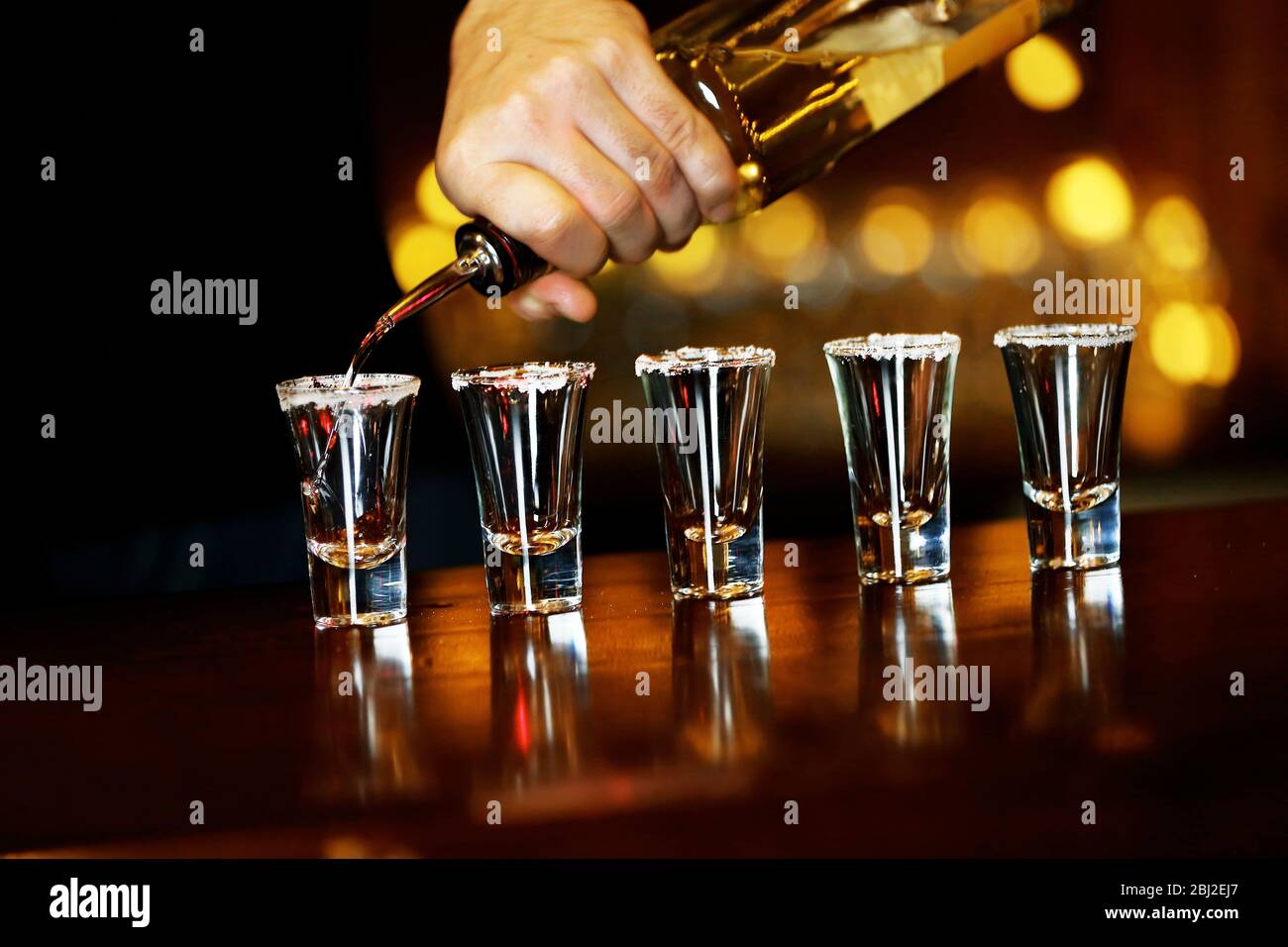 Bartender is pouring tequila into glass Stock Photo - Alamy