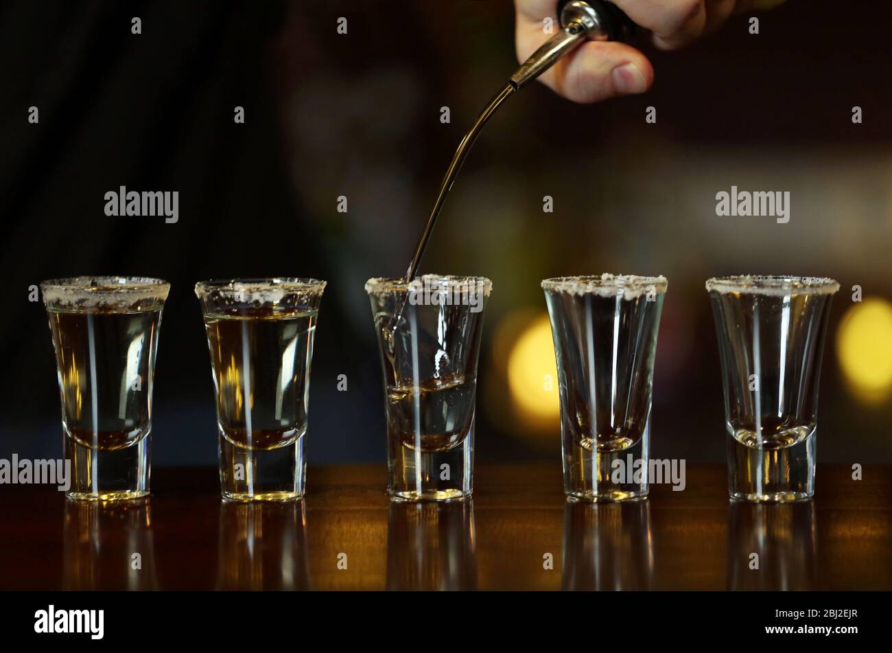 Bartender is pouring tequila into glass Stock Photo - Alamy