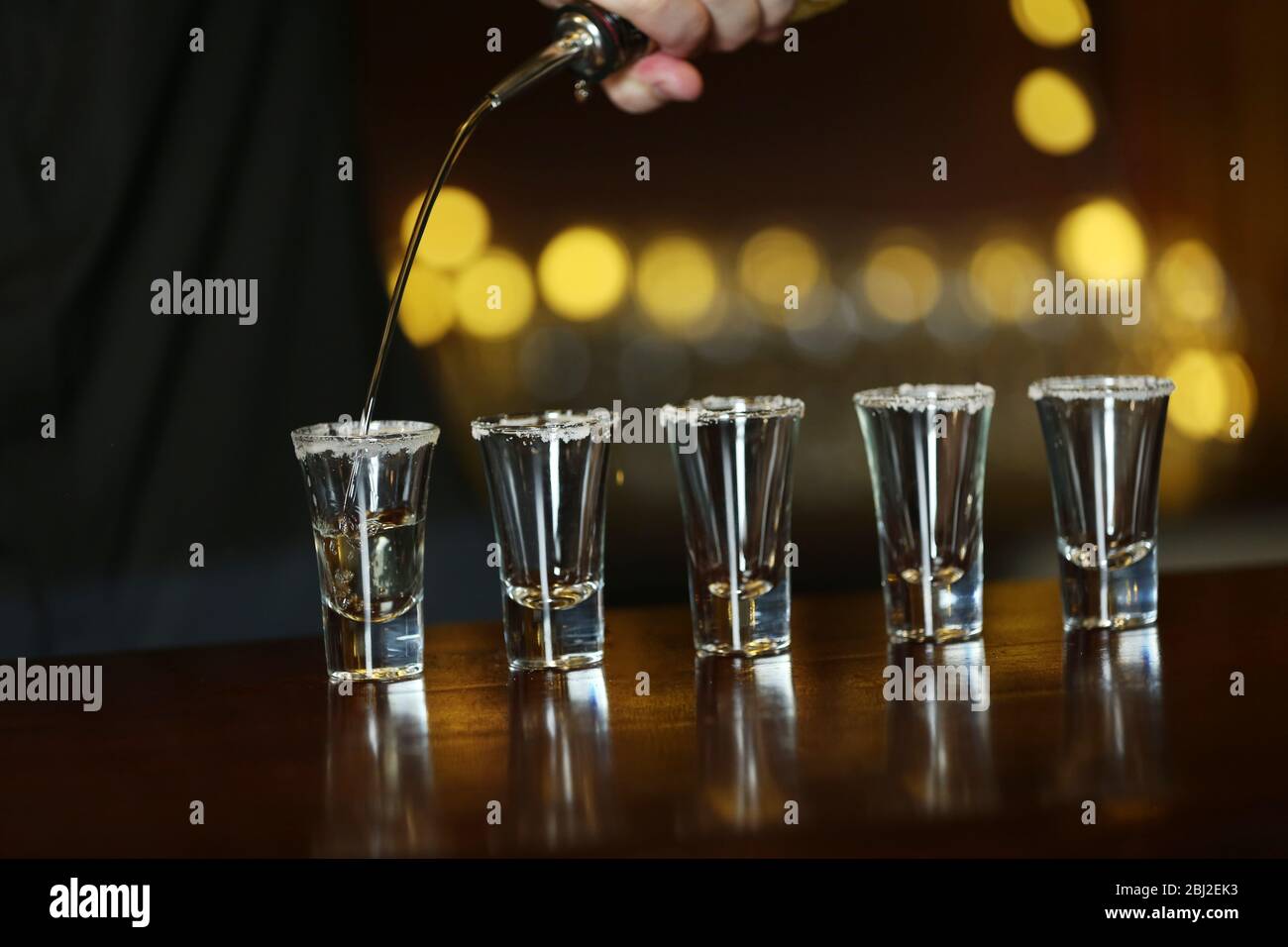 Bartender is pouring tequila into glass Stock Photo - Alamy