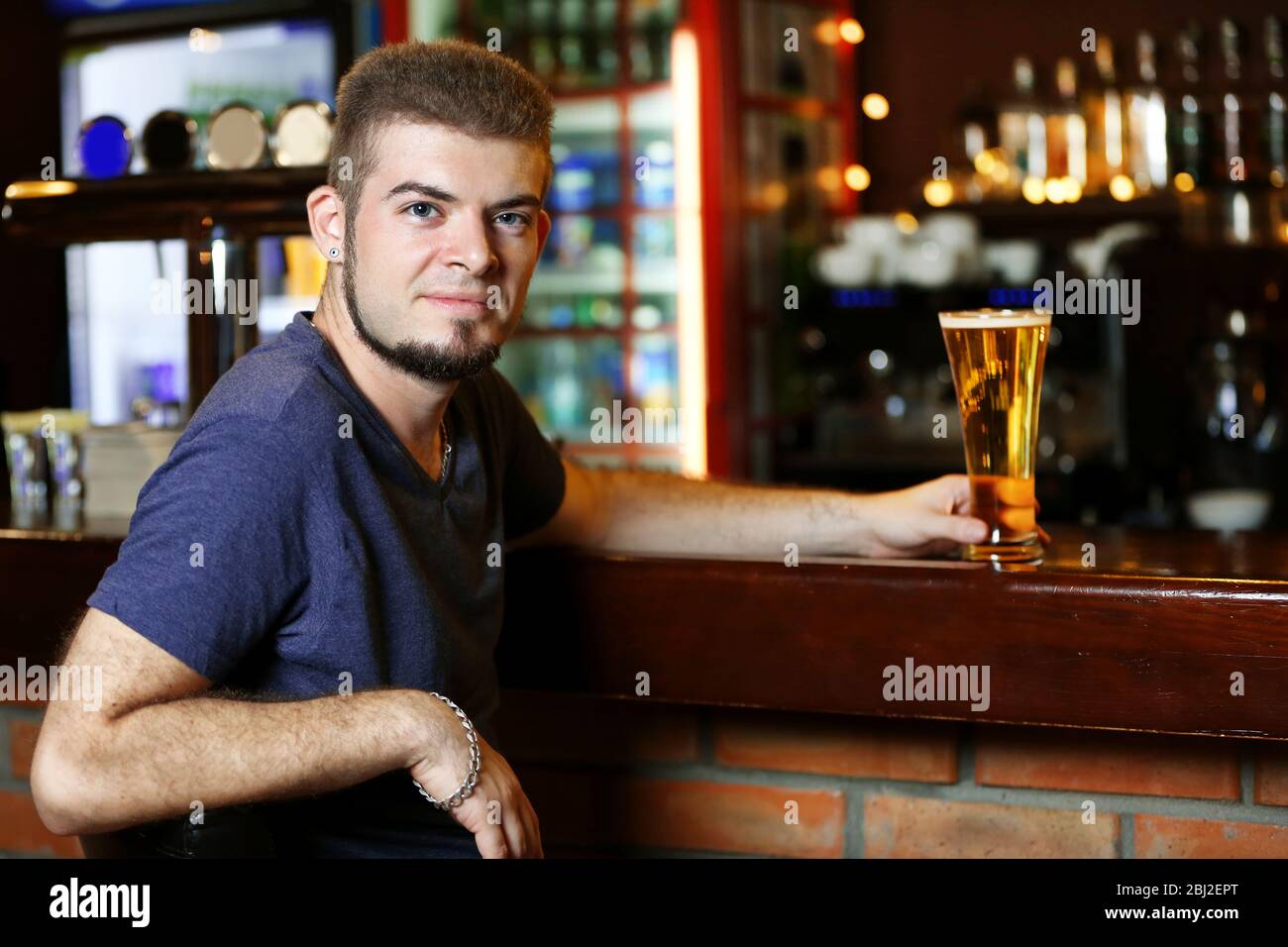 Young man drinking beer in bar Stock Photo - Alamy