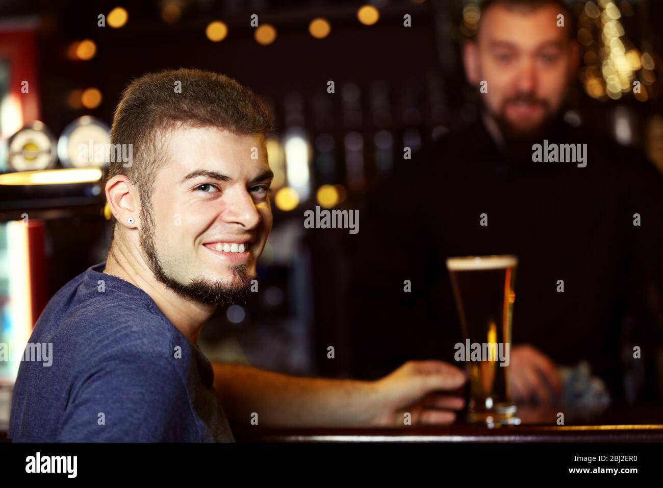 Young man drinking beer in bar Stock Photo - Alamy