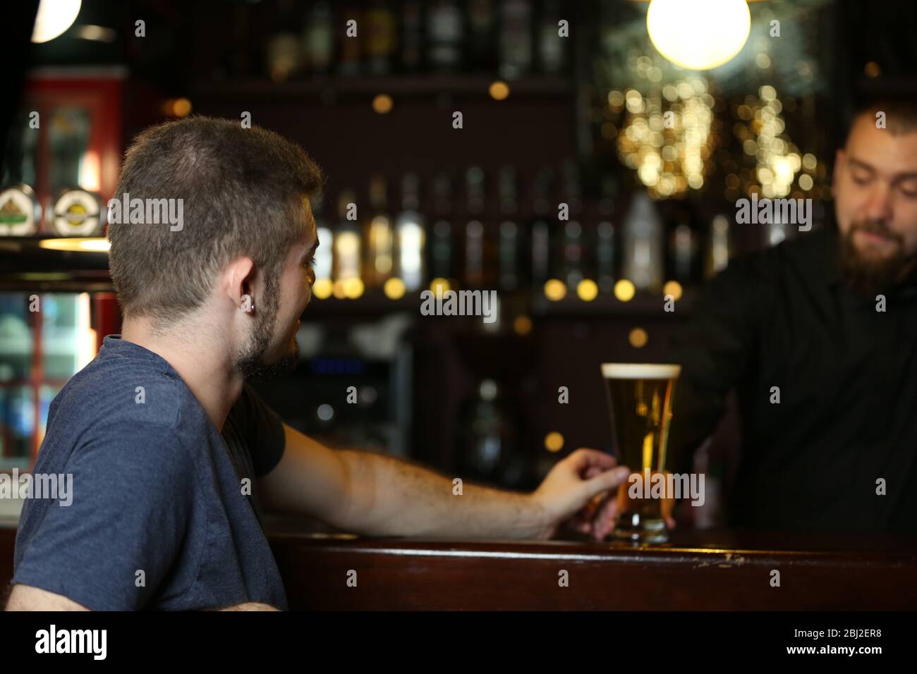Young man drinking beer in bar Stock Photo - Alamy