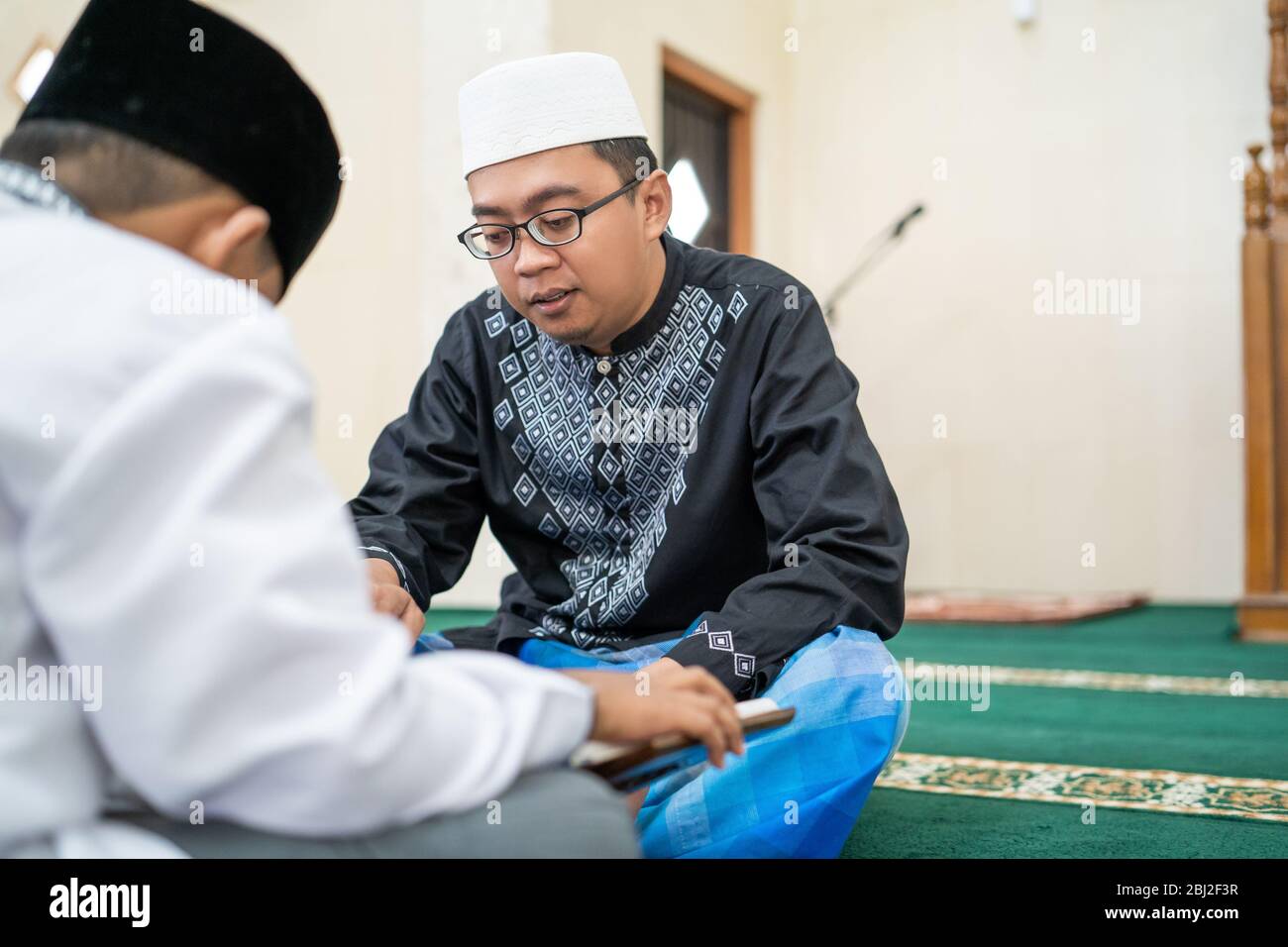 teacher is teaching muslim kid how to read holy quran in the mosque ...
