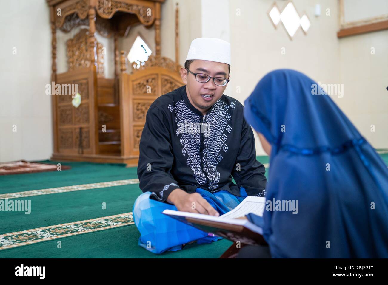 teacher is teaching muslim kid how to read holy quran in the mosque ...