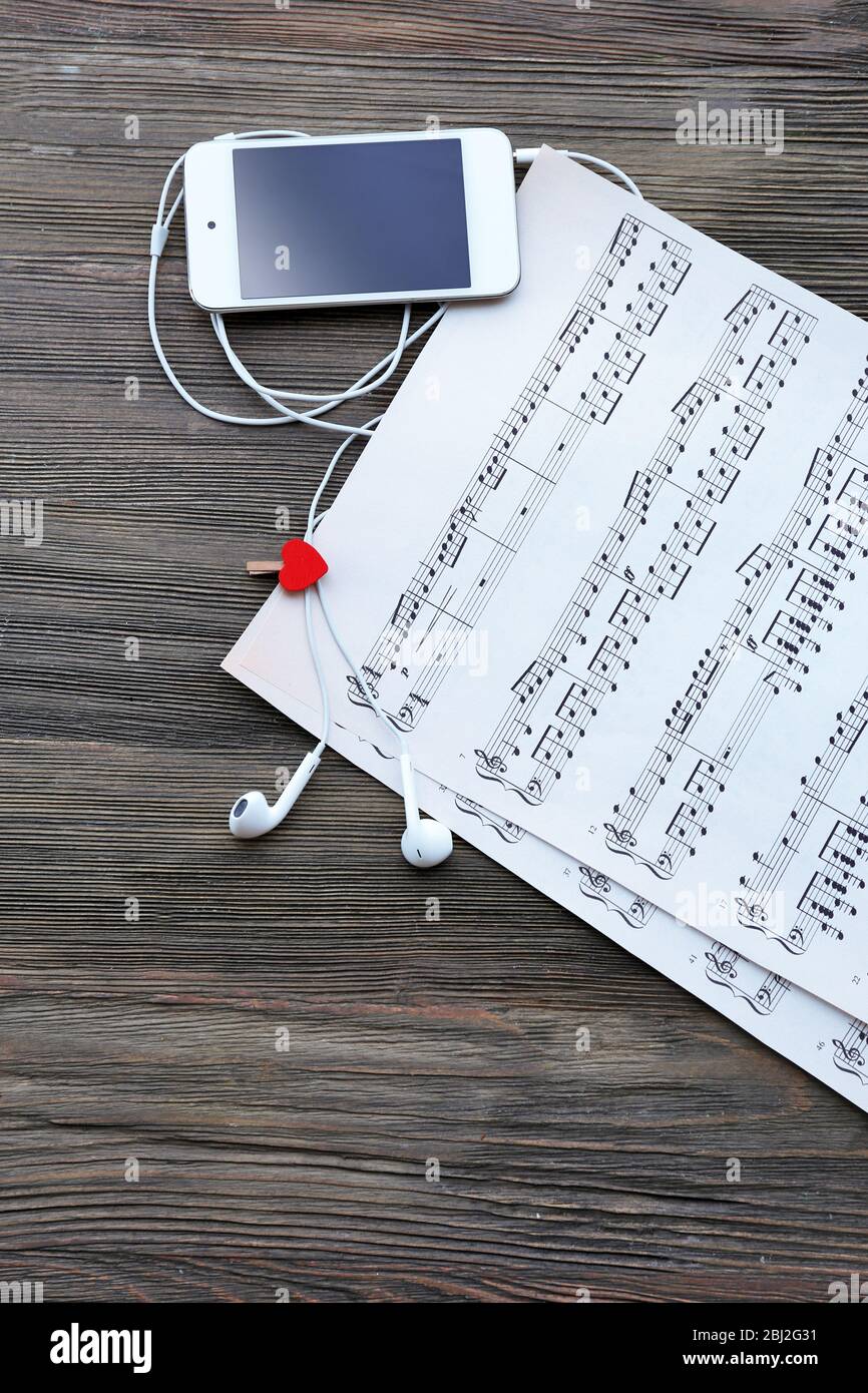 Mobile phone and earphones with music notes on wooden background Stock ...