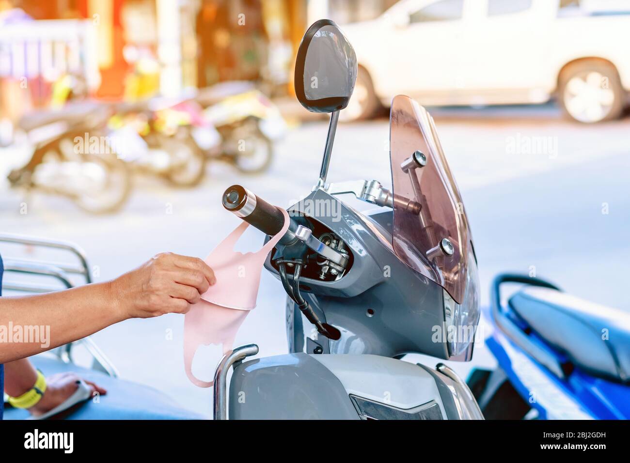 Hand of woman is picking a mask that is hung on a motorcycle handle to ...