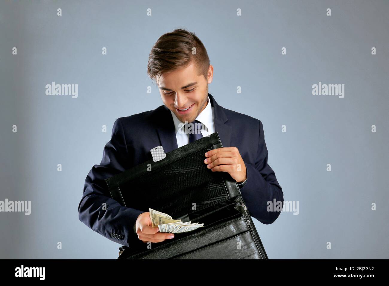 Business man hiding money in briefcase on gray background Stock Photo ...