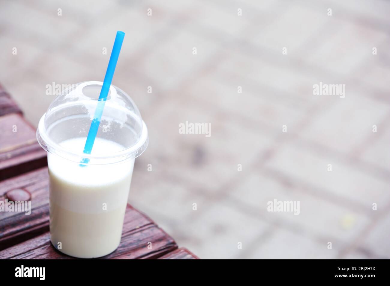 Plastic cup of milkshake on wooden bench, outdoors Stock Photo - Alamy