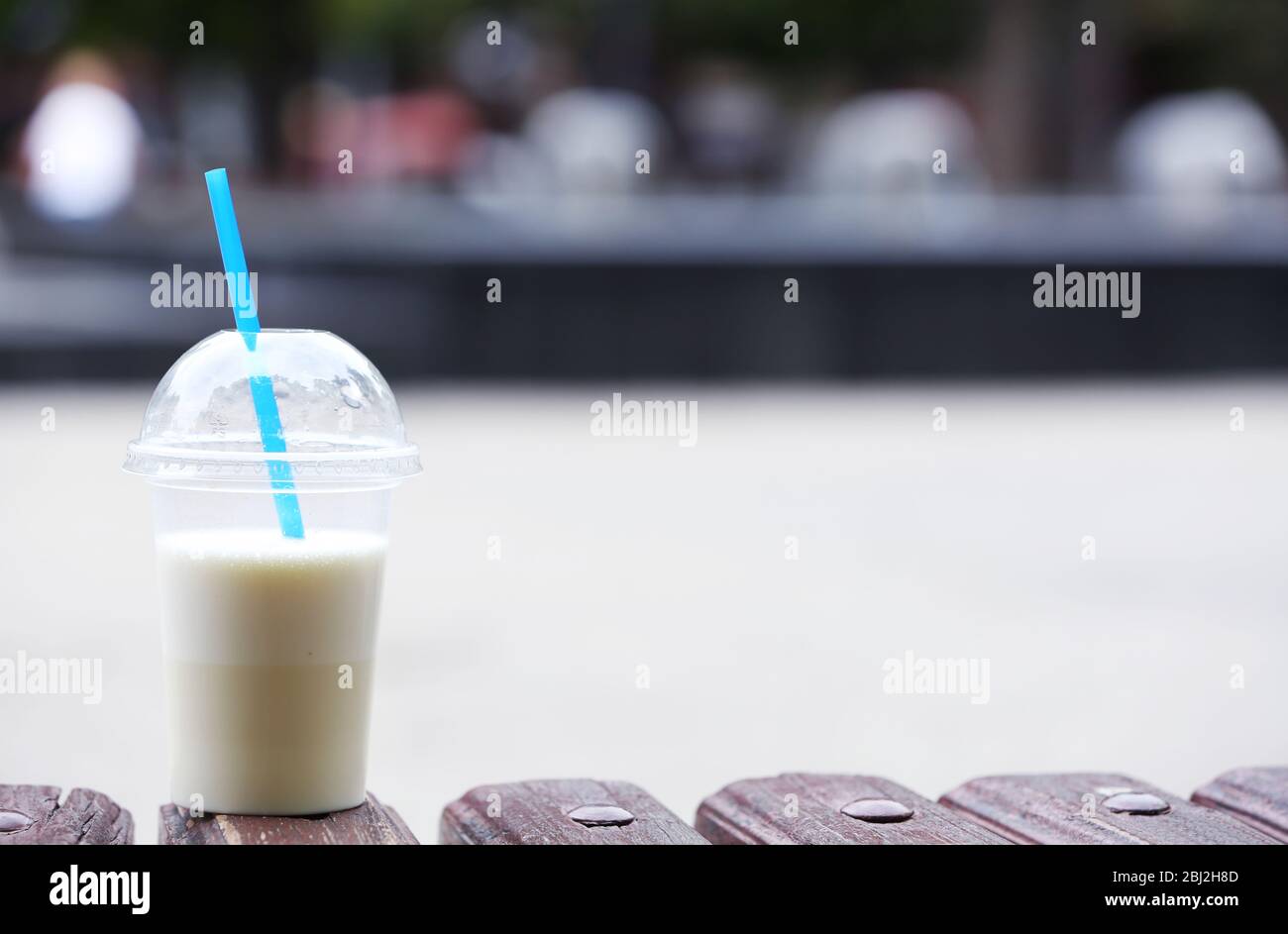 Plastic cup of milkshake on wooden bench, outdoors Stock Photo - Alamy