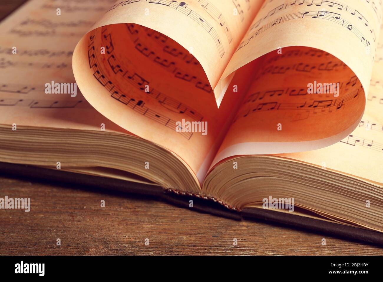Book pages curved into heart shape close up Stock Photo - Alamy