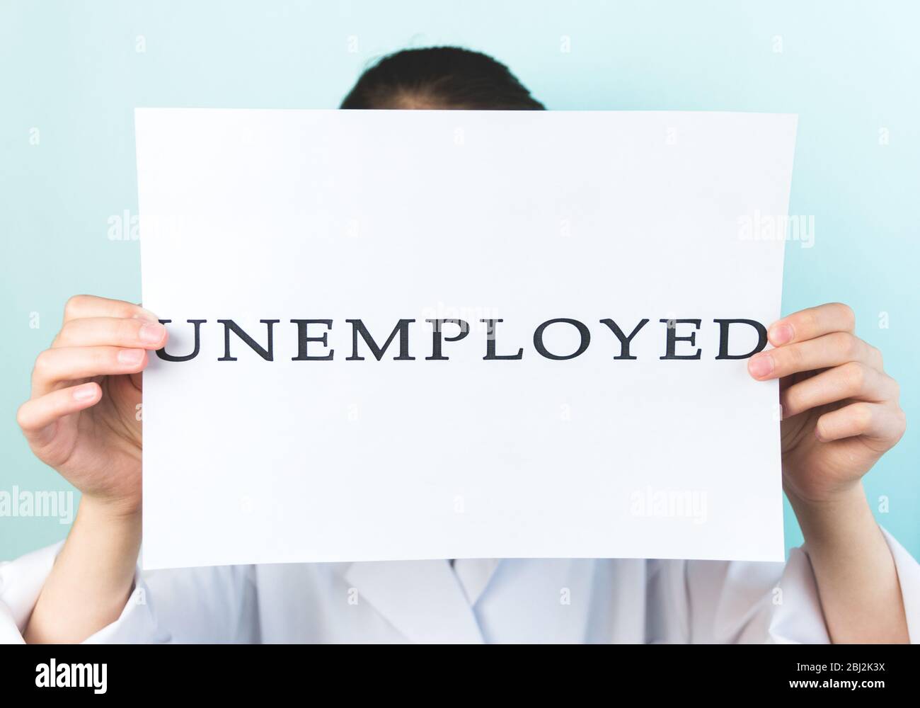 A white paper sheet with the words unemployed in hands. The jobless ...