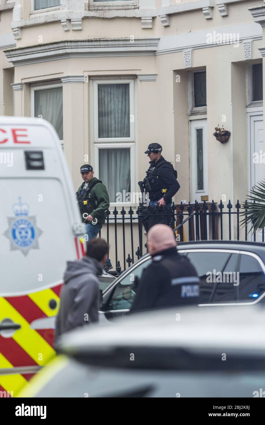 Eastbourne, England. 28 Apr 2020. Armed police leave the raided ...