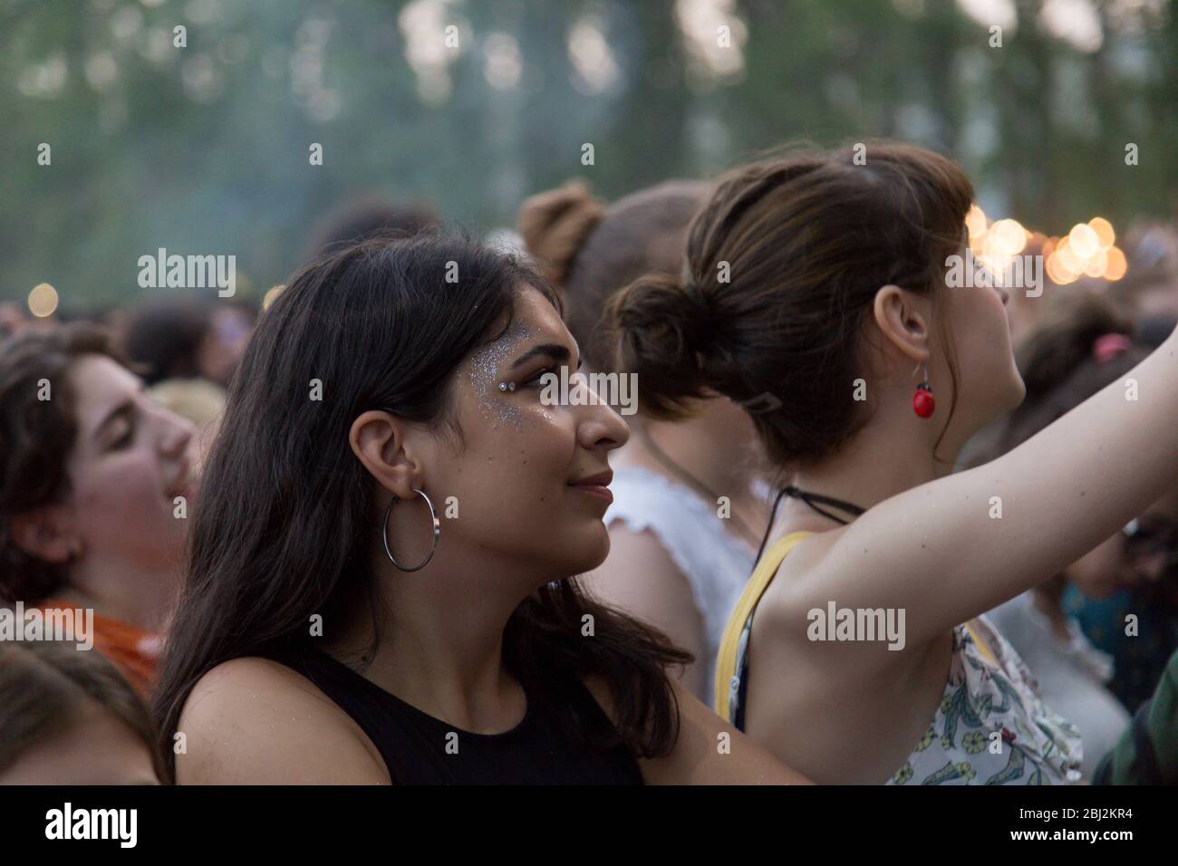 Audience with hands raised at a music festival and lights streaming ...