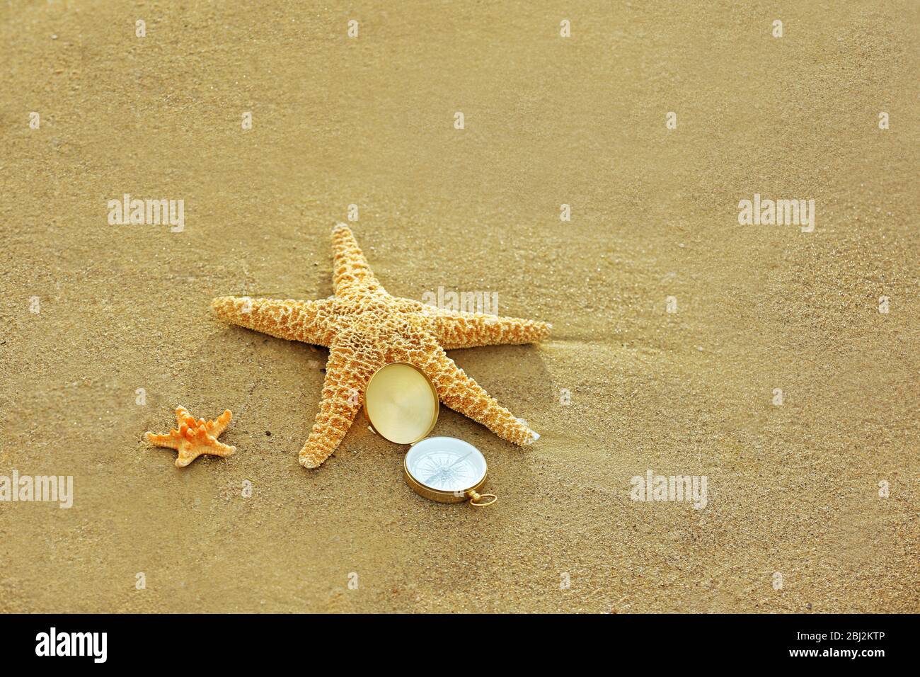 Compass with sea stars on sand beach background Stock Photo - Alamy