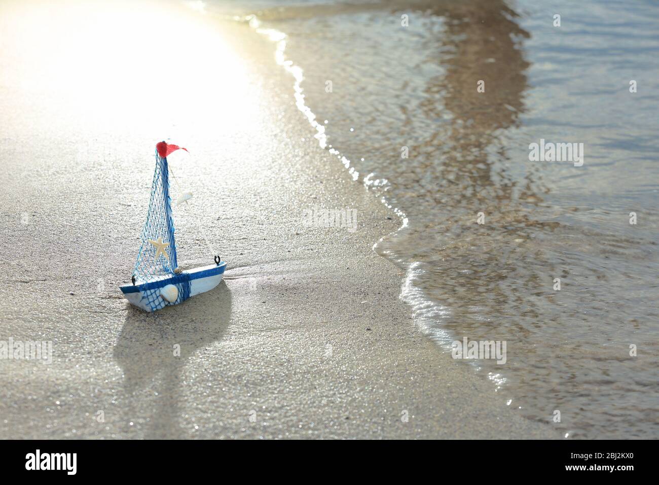Small ship on sand beach background Stock Photo - Alamy